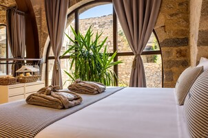 Quarto de hotel com cama, toalhas, uma planta e vista para o exterior.