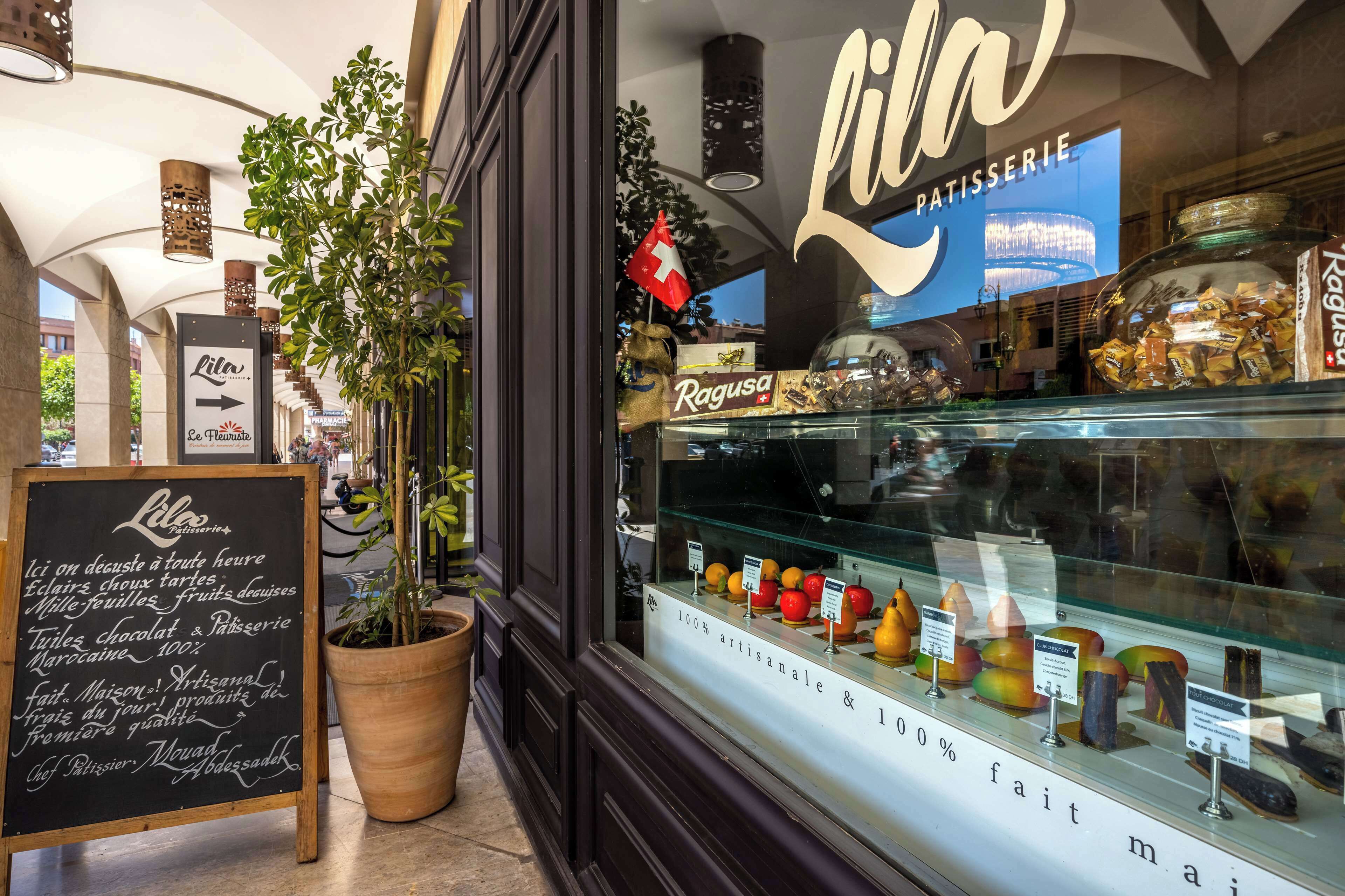 Vitrine com um letreiro de 'Lila Patisserie' e uma vitrine expõe diversos doces.