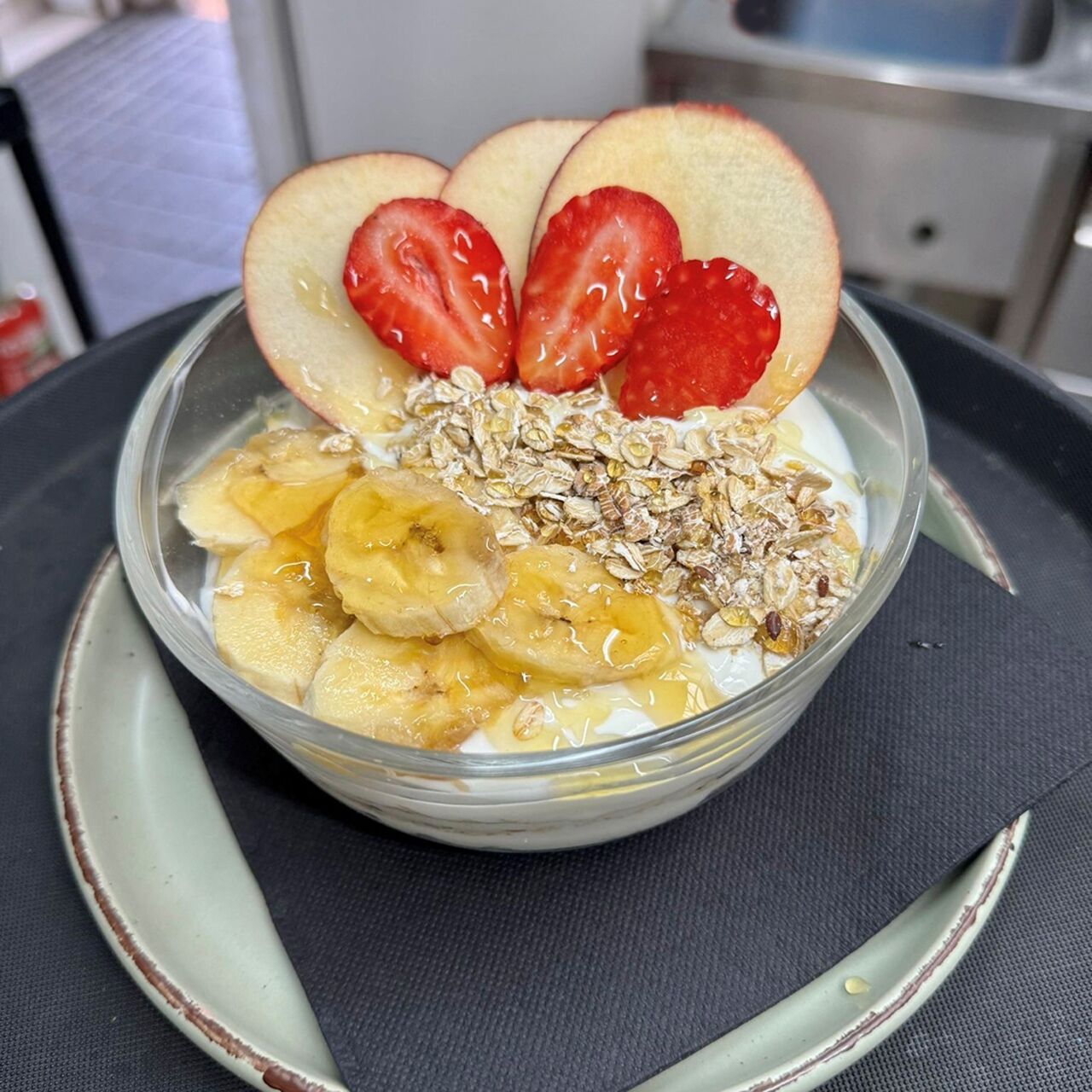 Uma tigela de cereais com bananas em rodelas, morangos e aveia num prato.