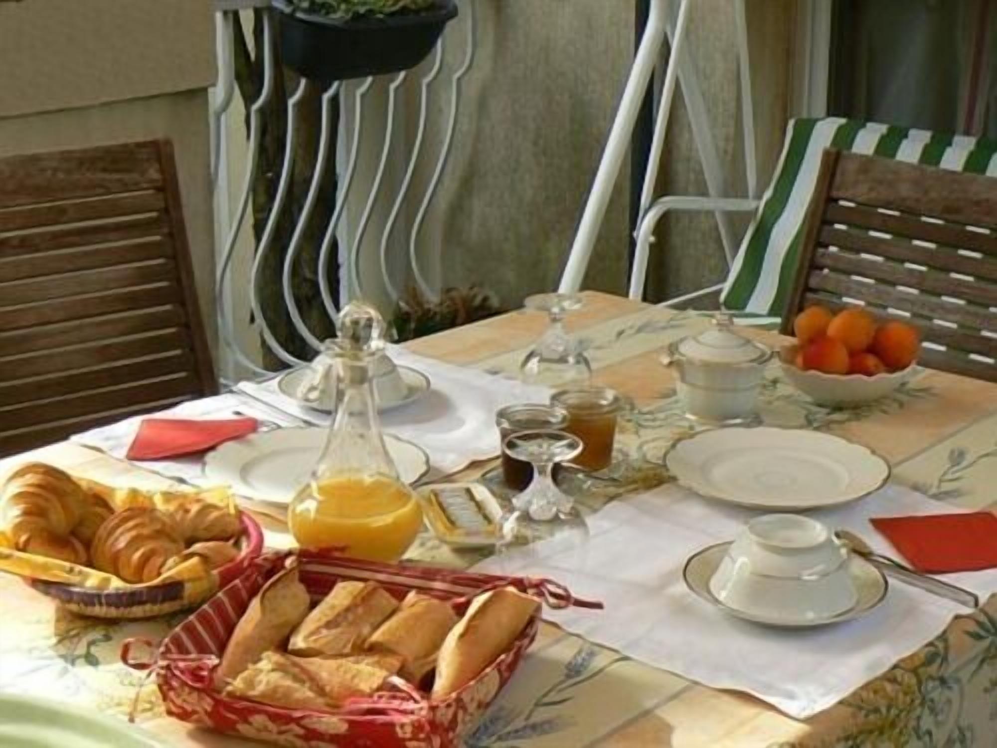 Uma mesa de café da manhã com croissants, suco de laranja e uma fruteira.