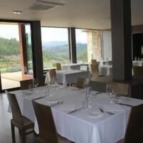Restaurante com mesas preparadas para refeições, amplas janelas com vista para o exterior.