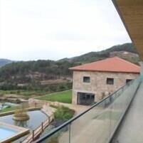 Vista de varanda com vista para uma piscina, um edifício de pedra e uma paisagem montanhosa.