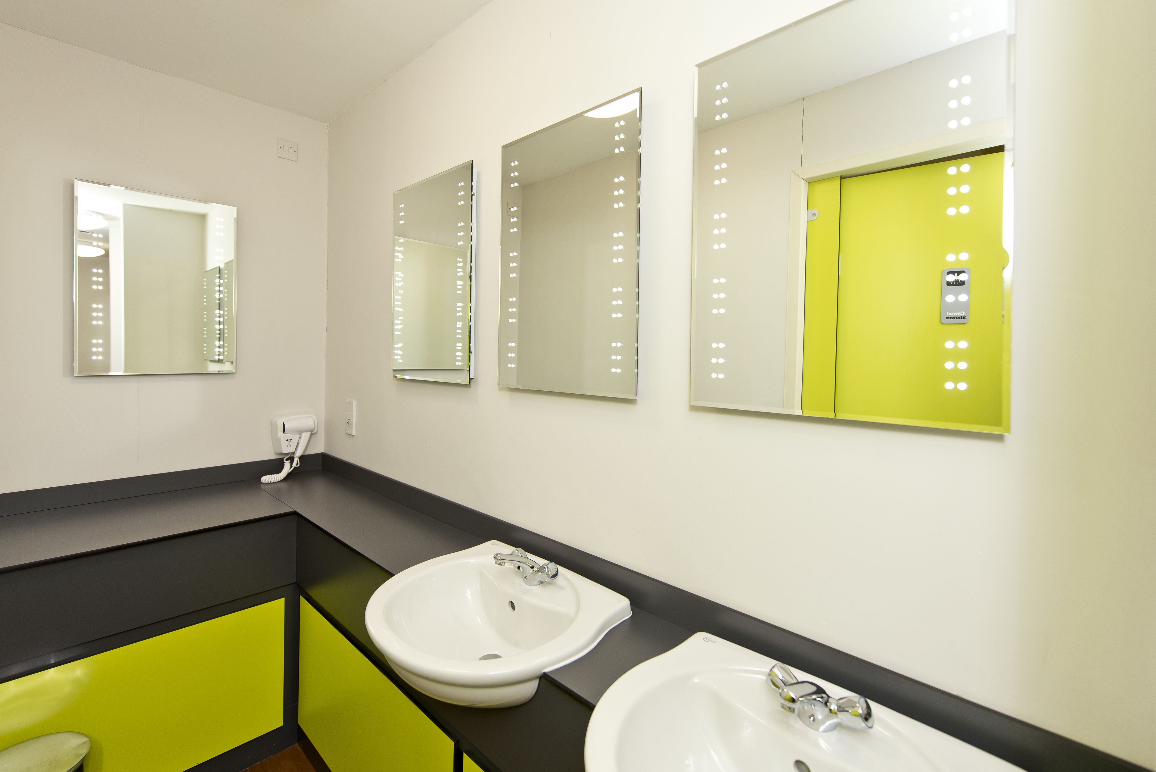 Uma casa de banho moderna com duas pias, um espelho e uma porta verde.