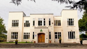 Um edifício com fachada simétrica, várias janelas e entrada central com porta.