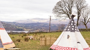 Um camping com duas tendas estilo tipi, cada uma com uma mesa de piquenique na frente.