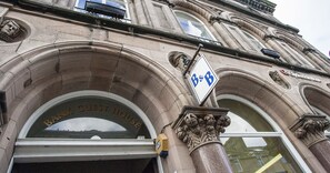 Fachada de edifício com entrada em arco identificada como "Bank Guest House".