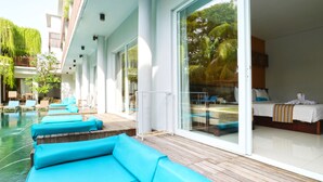 Um hotel com área de piscina, com cadeiras de descanso azuis e um deck de madeira.