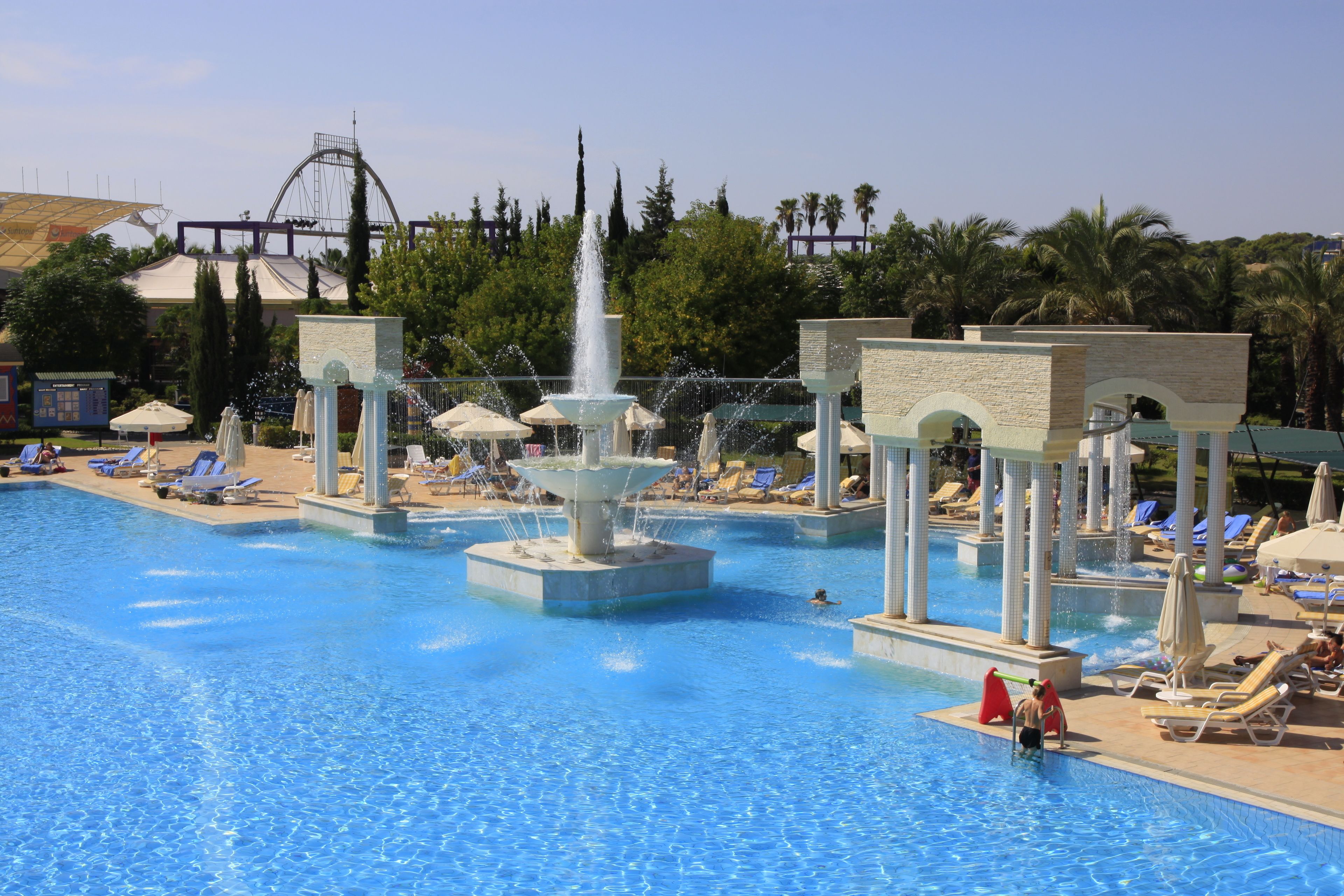 Piscina com várias fontes, espreguiçadeiras e guarda-sóis.