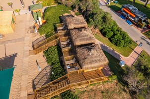 Um resort com cabanas de telhado de palha, piscina e food truck.