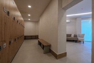 Um corredor com armários identificados de 5 a 8, um banco e uma área de estar com um sofá e uma cadeira.