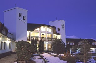 Um hotel moderno com varanda, paisagem coberta de neve e céu claro.
