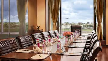 Uma sala de conferência com uma mesa comprida, cadeiras de couro e vista para um aeroporto.