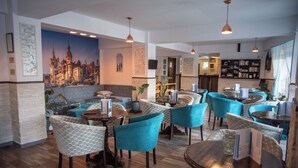 Um saguão de hotel com áreas de estar, um grande mural e uma estante de livros.
