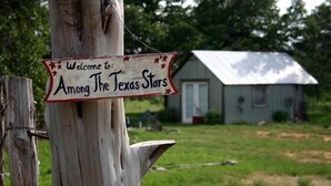 Um poste de madeira com uma placa que diz 'Welcome to Among The Texas Stars'.