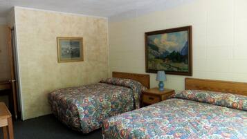 Quarto com duas camas de solteiro, uma mesa de cabeceira de madeira com abajur, um quadro de paisagem na parede e uma porta que dá para outro quarto.