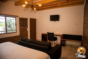 Quarto com cama, escrivaninha, cadeira e televisão.