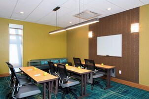 Uma sala de conferências com uma mesa comprida, cadeiras, um quadro branco e uma tela de projeção.