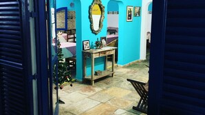 Um quarto com piso de azulejos, uma mesa de madeira, uma árvore de Natal e um espelho na parede.