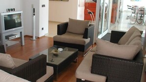 Uma sala de estar com televisão, dois sofás, uma mesa de centro e um alto-falante.