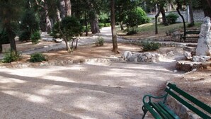 Um parque com um caminho pavimentado, bancos e esculturas de pedra.