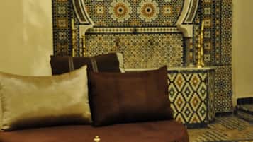 Um quarto com parede estampada, um sofá, uma mesa de centro com objetos decorativos e piso estampado.