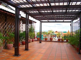 Uma área externa coberta com piso de azulejos e plantas em vasos.