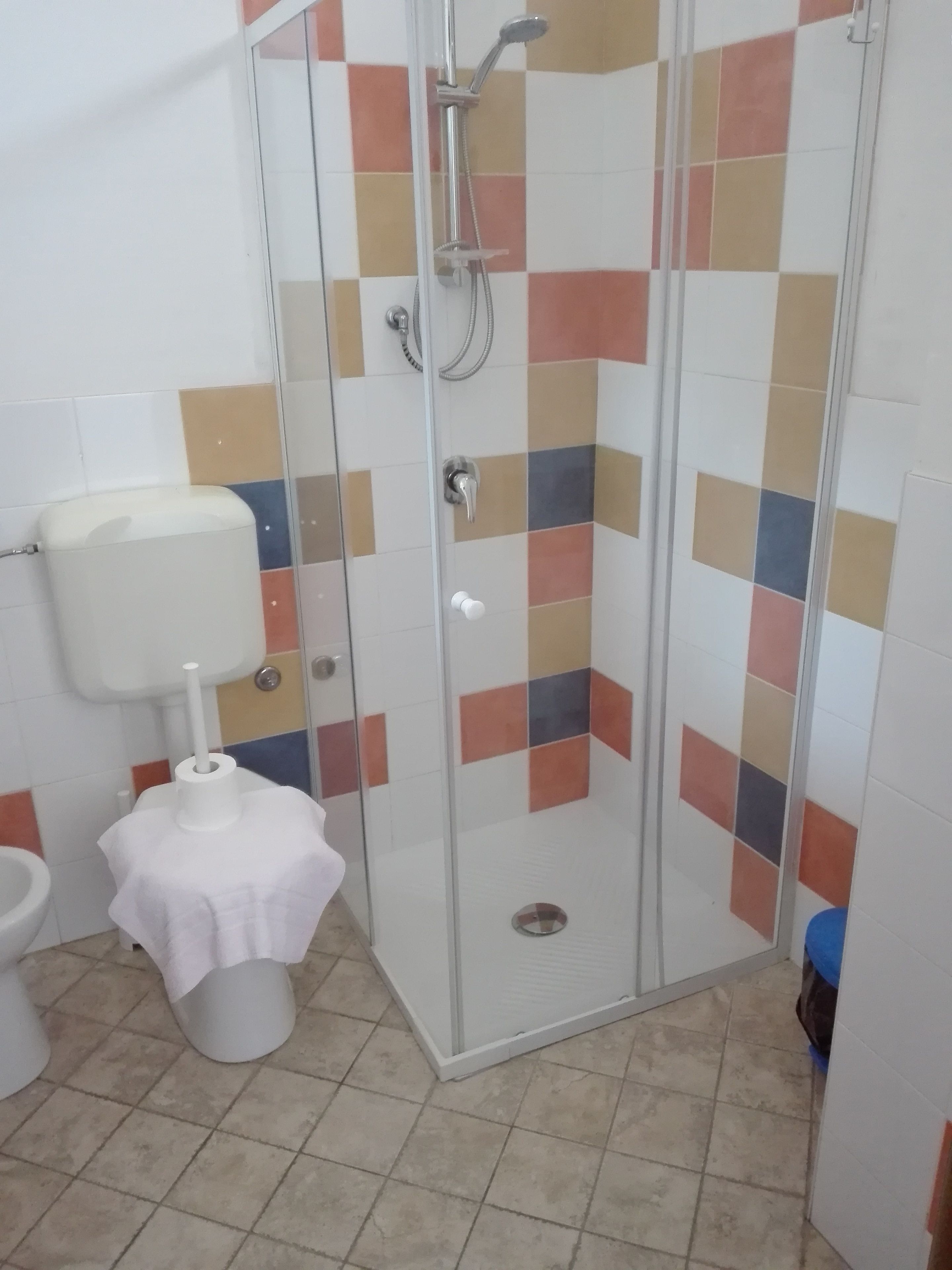 Casa de banho com chuveiro de cabine de vidro, sanita e bidé.