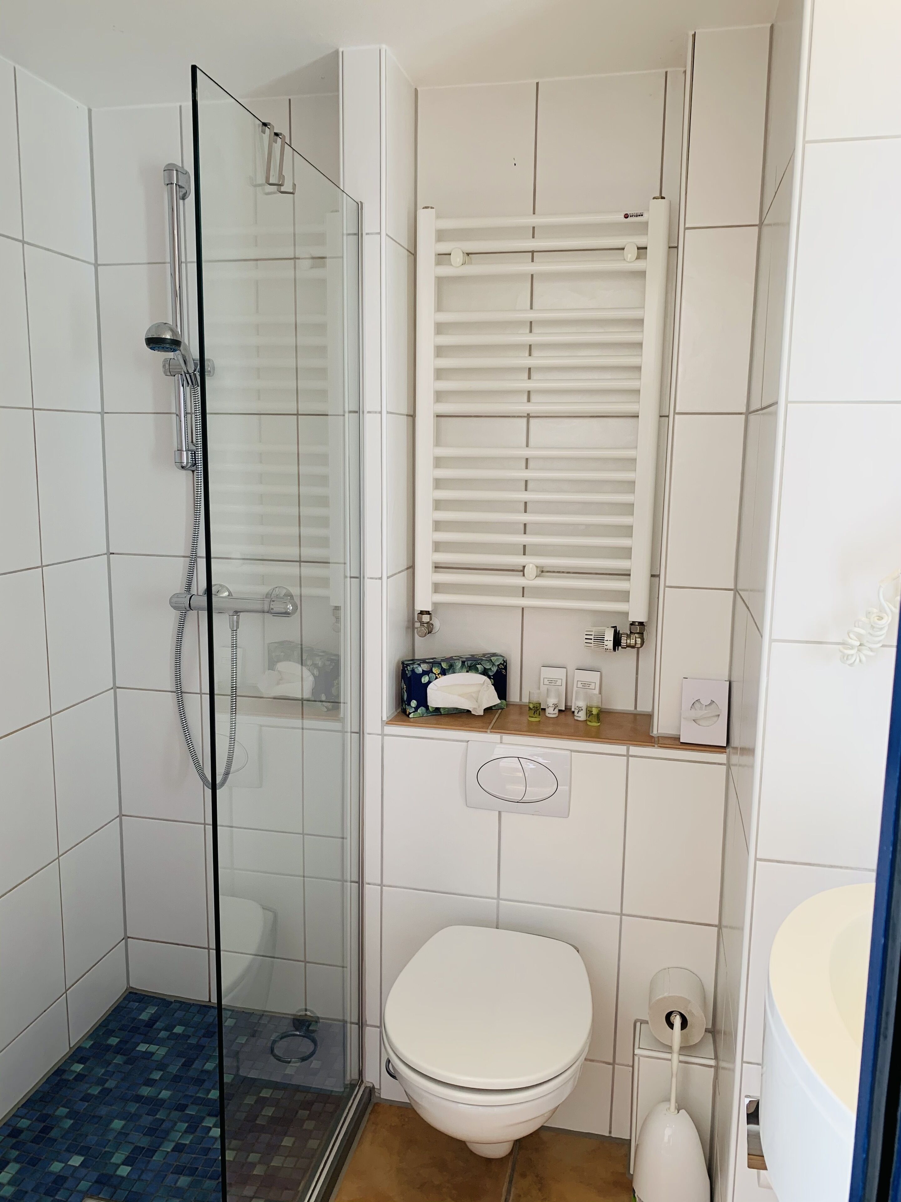 Casa de banho com cabine de duche em vidro, sanita e lavatório com espelho em cima.