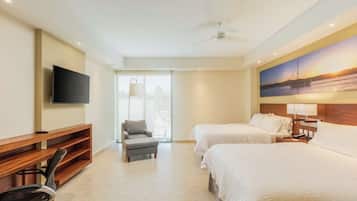 Quarto de hotel com duas camas, uma escrivaninha, uma cadeira, uma televisão e uma pintura do pôr do sol sobre a água.