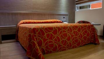 Quarto de hotel com cama, mesa de cabeceira e janela.