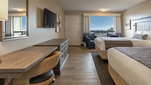 Quarto de hotel com escrivaninha de madeira, duas camas, televisão e varanda com vista.