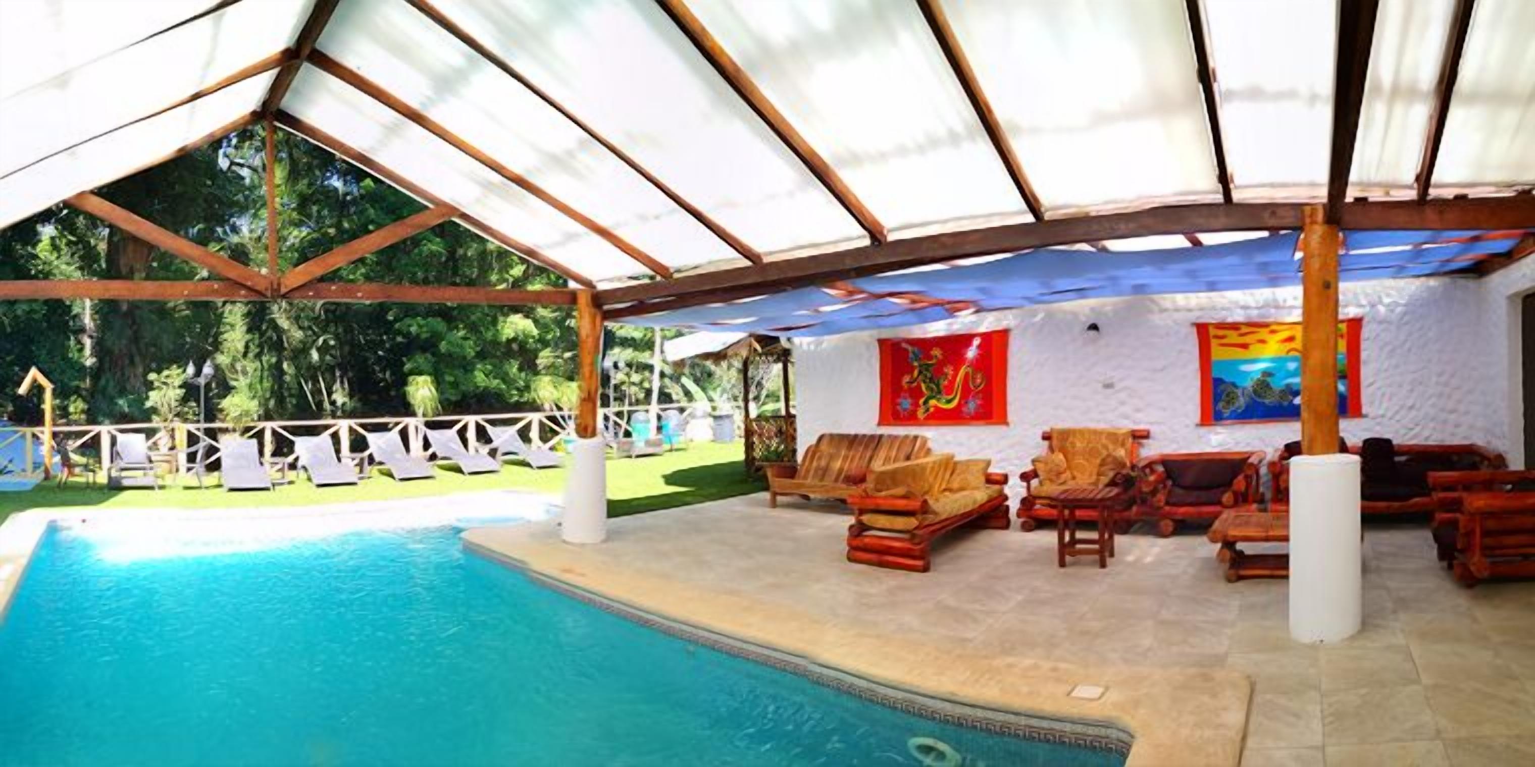 Uma área de piscina interna com terraço coberto, espreguiçadeiras e piscina.
