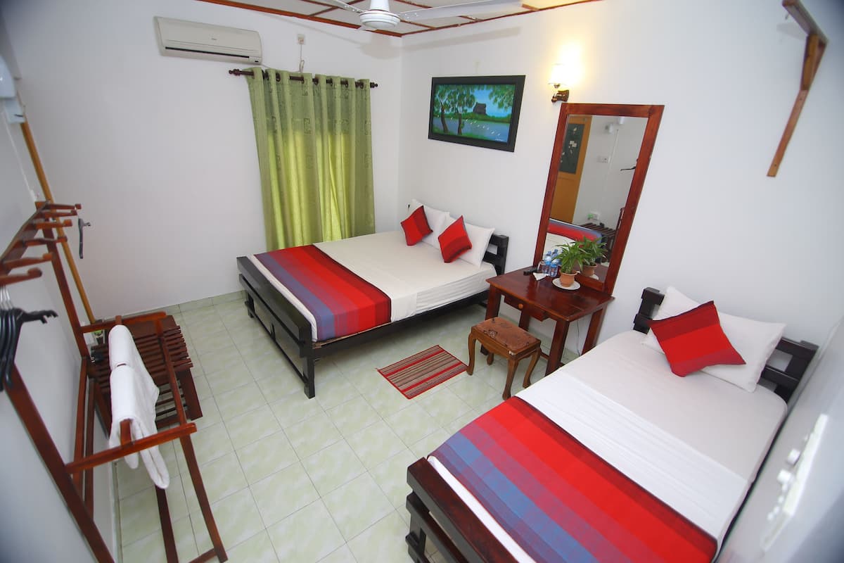 Quarto de hotel com duas camas, uma mesa, uma cadeira, um espelho, janela com cortinas e televisão fixada na parede.