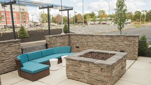 Uma área de pátio externo com uma lareira de pedra e um sofá modular azul.