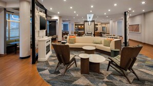 Um saguão de hotel moderno com uma área de estar em curva, uma TV de tela plana e um espaço para refeições.
