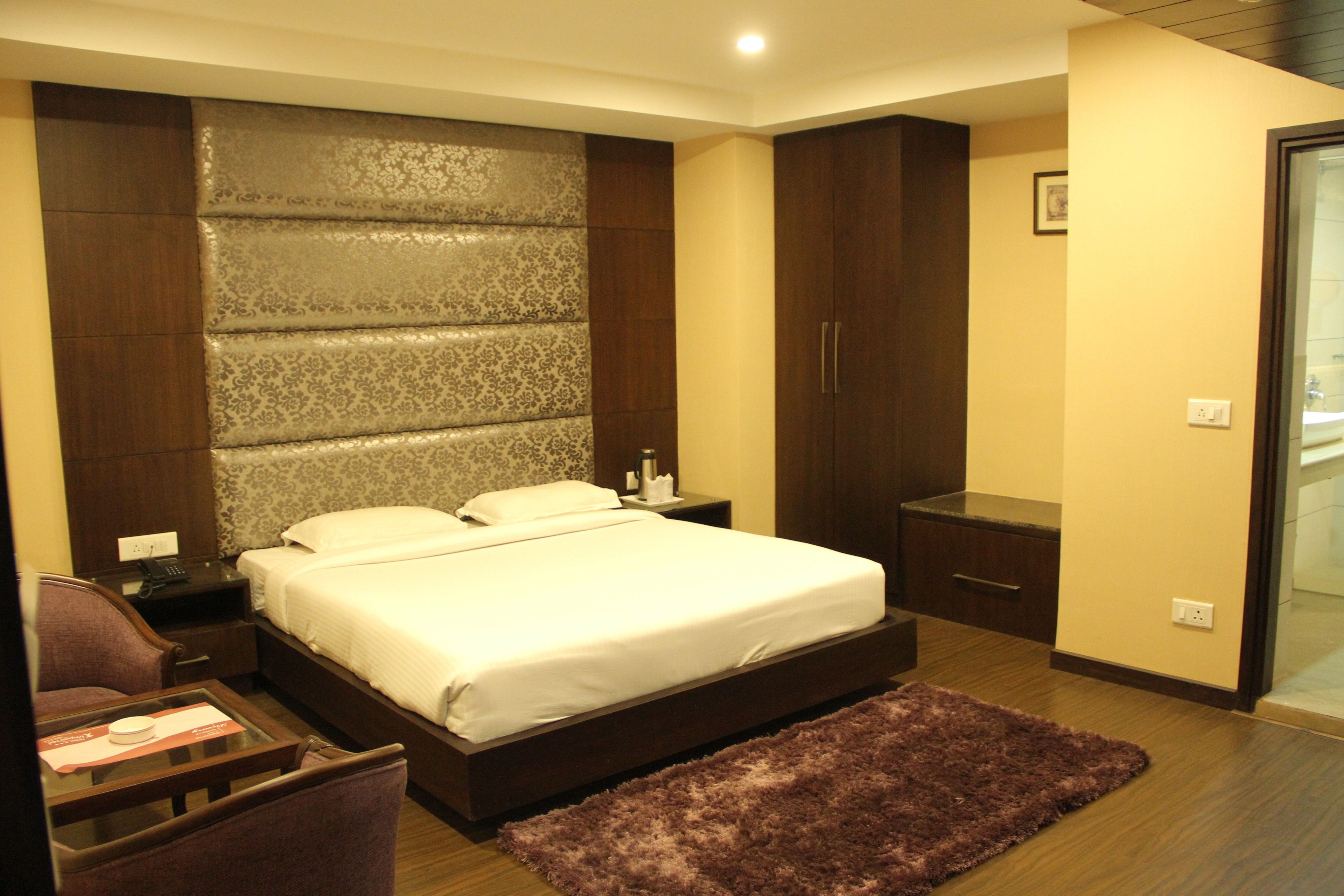 Um quarto moderno com uma cama grande, uma mesa de cabeceira, uma cadeira e um guarda-roupa.