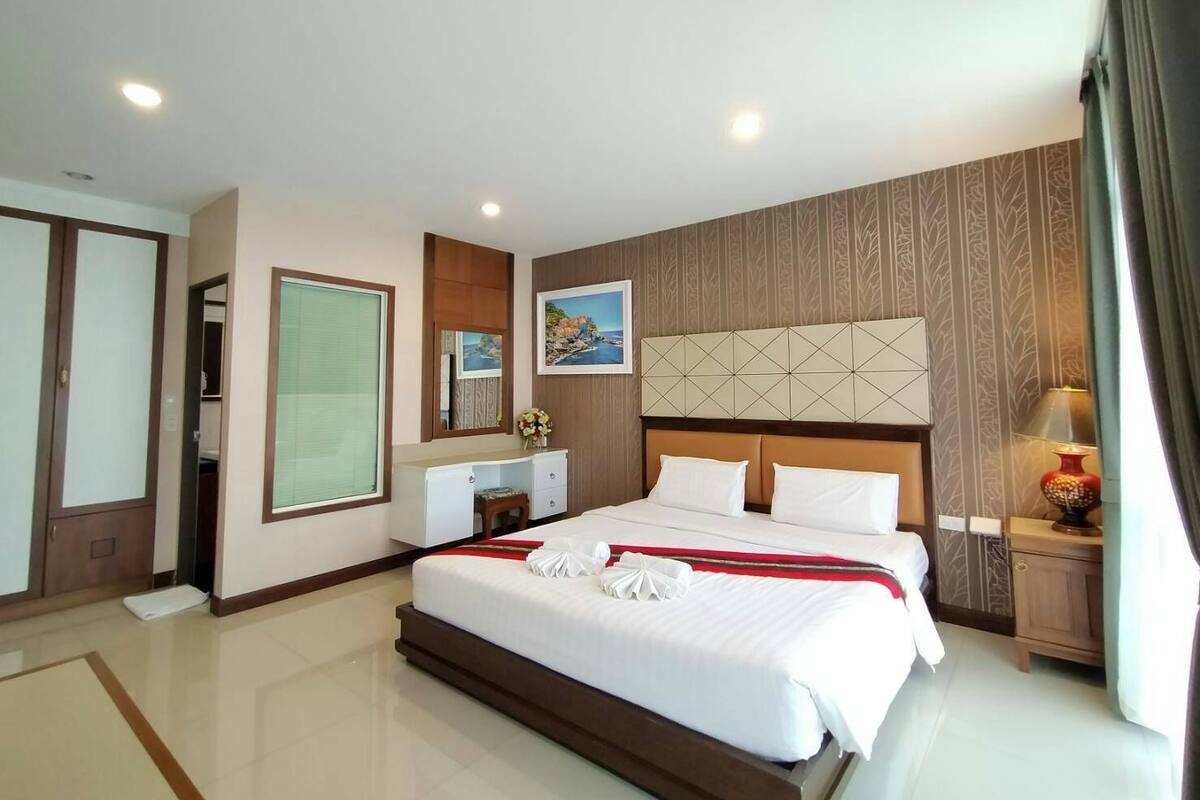 Quarto de hotel com uma cama grande, uma escrivaninha, um espelho e um quadro na parede.