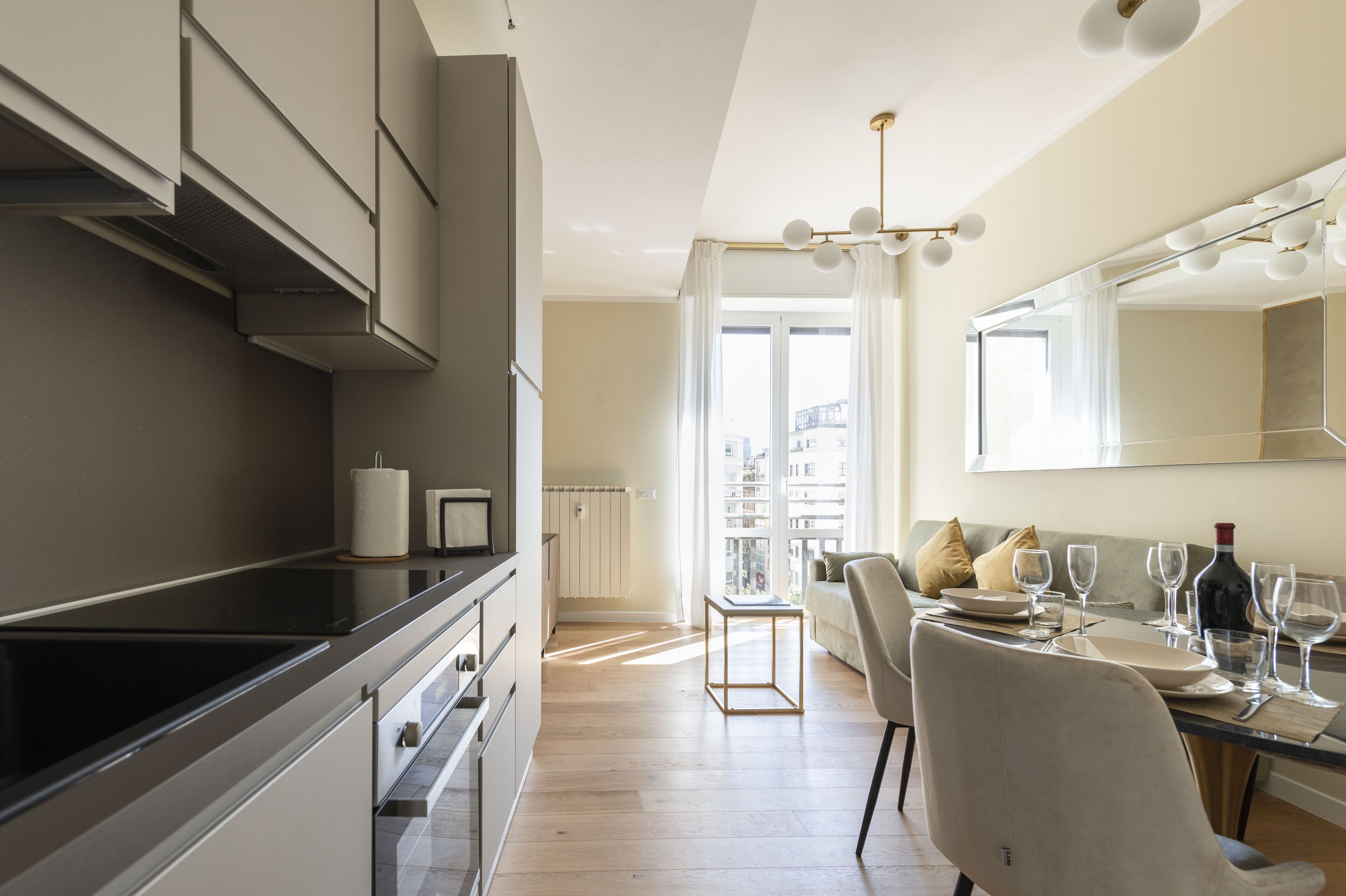 Cozinha moderna com bancada preta, armários brancos e área de jantar com mesa posta para quatro pessoas.
