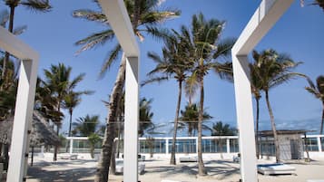 Praia particular, areia branca, espreguiçadeiras, guarda-sóis