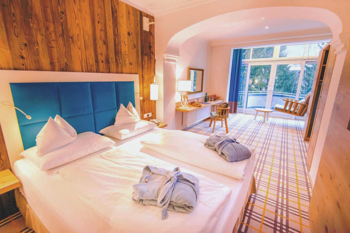 Quarto de hotel com duas camas, uma escrivaninha e uma cadeira.