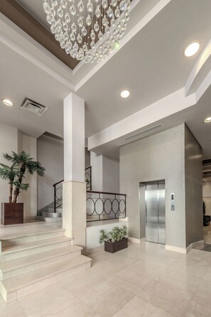 Um interior moderno com um lustre imponente, uma escadaria e um elevador.