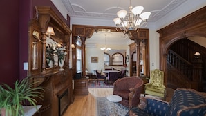 Uma sala de estar ampla com lareira, um candelabro e uma escada.