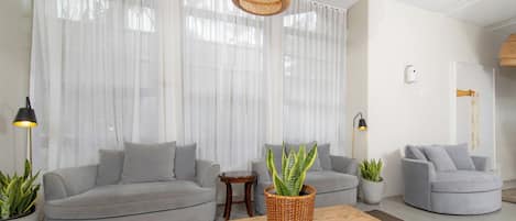 Uma sala de estar moderna com sofás cinza, uma mesa de centro de madeira e plantas em vasos.
