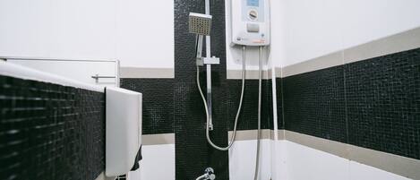 Casa de banho com parede em azulejos preto e branco, cabine de duche branca e painel de controlo.