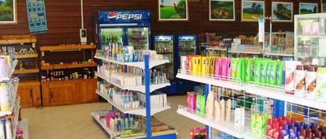 Interior de loja com prateleiras repletas de diversos produtos, incluindo um refrigerador da Pepsi.