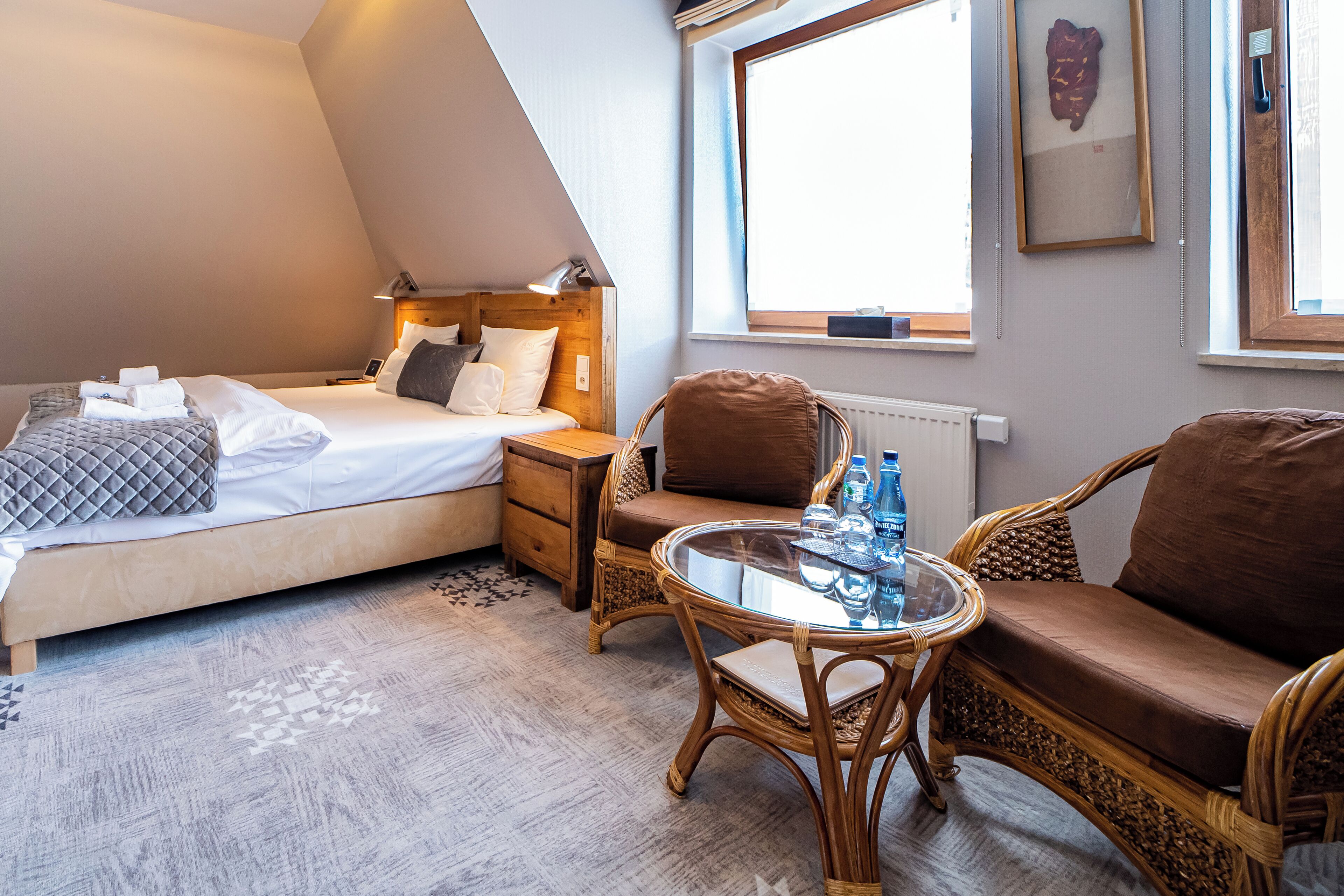 Quarto com cama, mesa de cabeceira e mesa de vidro com cadeiras.