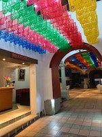 Uma área de recepção com uma placa que diz RECEPCION, piso de azulejos e decoração colorida no teto.