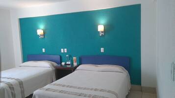 Quarto de hotel com duas camas de solteiro, paredes cor de verde-água e luminárias fixadas na parede.