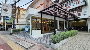 Um café moderno com mesas ao ar livre e um terraço coberto.