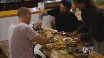 Um grupo de pessoas jantando em uma mesa de madeira com diversos pratos.